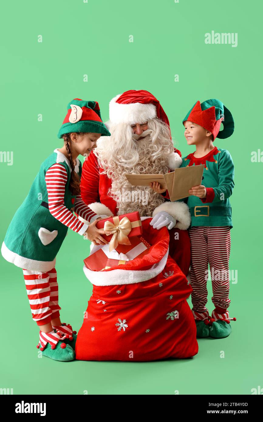 Little elves with letters and bag of gifts helping Santa Claus on green ...