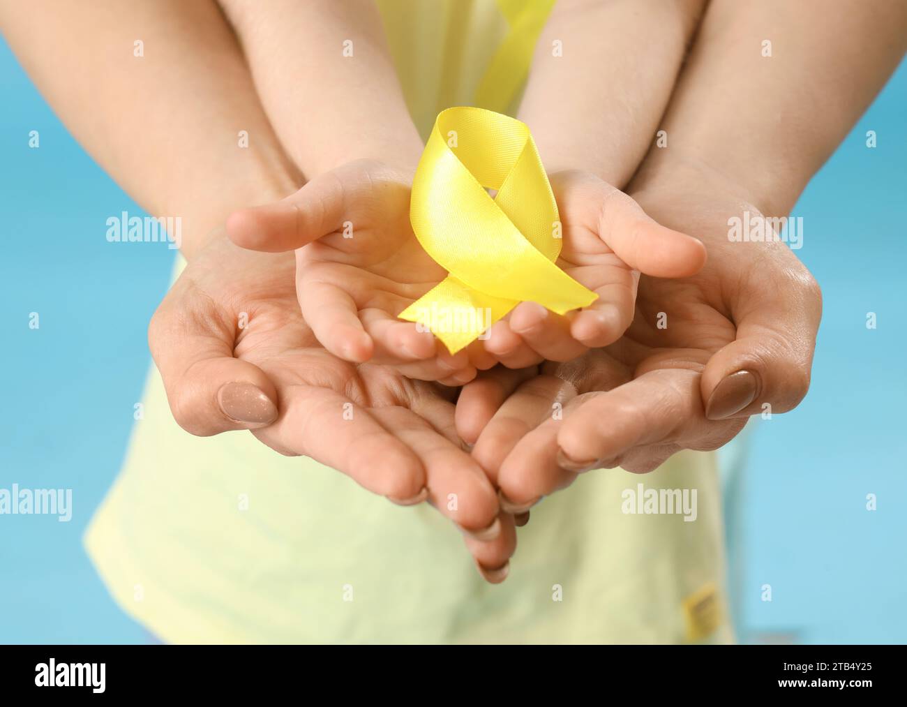Little girl after chemotherapy with nurse and ribbon on blue background ...