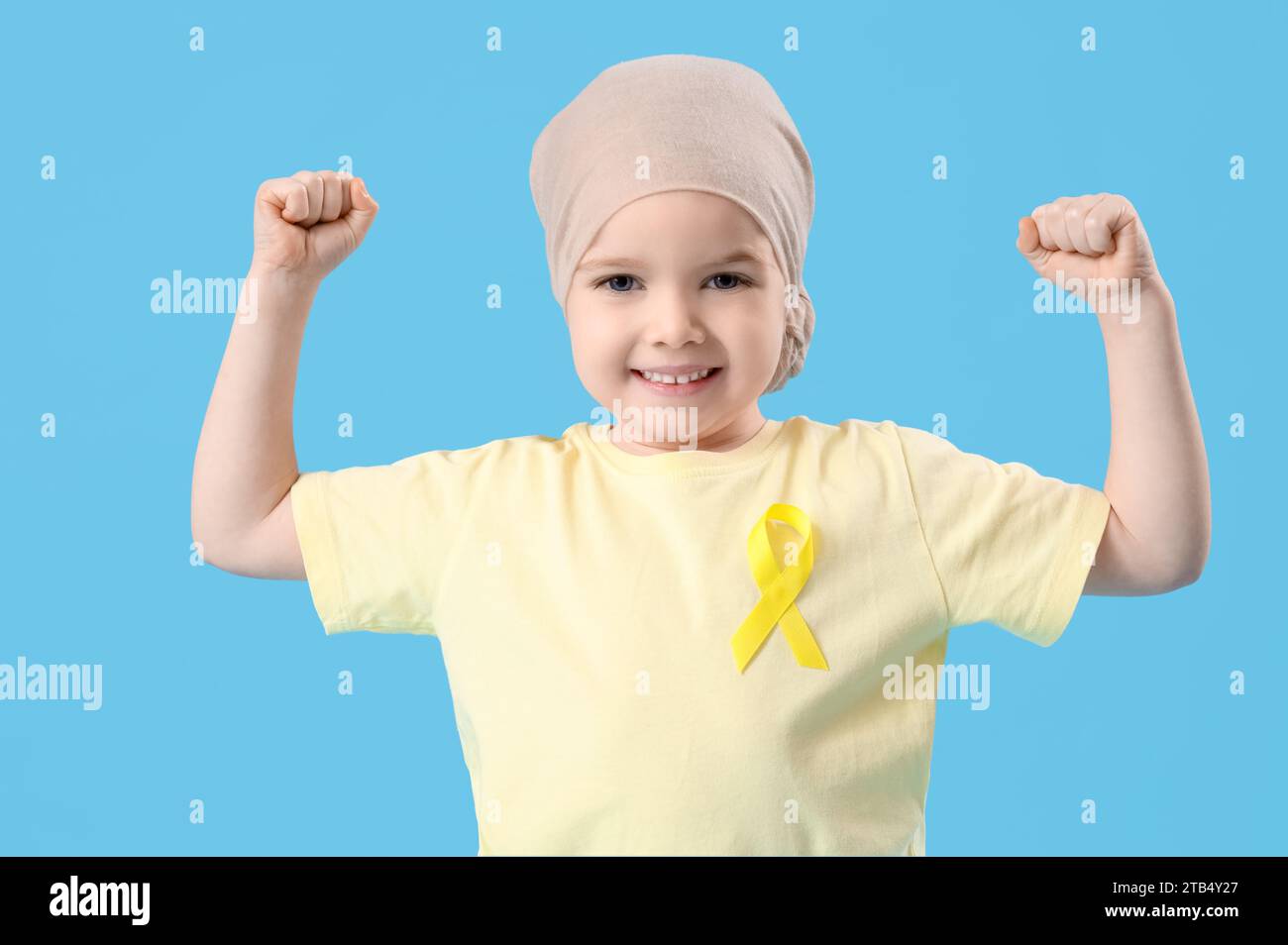 Little girl after chemotherapy with ribbon showing muscles on blue ...