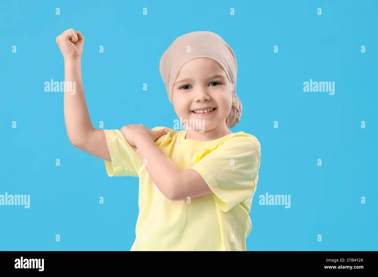 Little girl after chemotherapy showing muscles on blue background ...