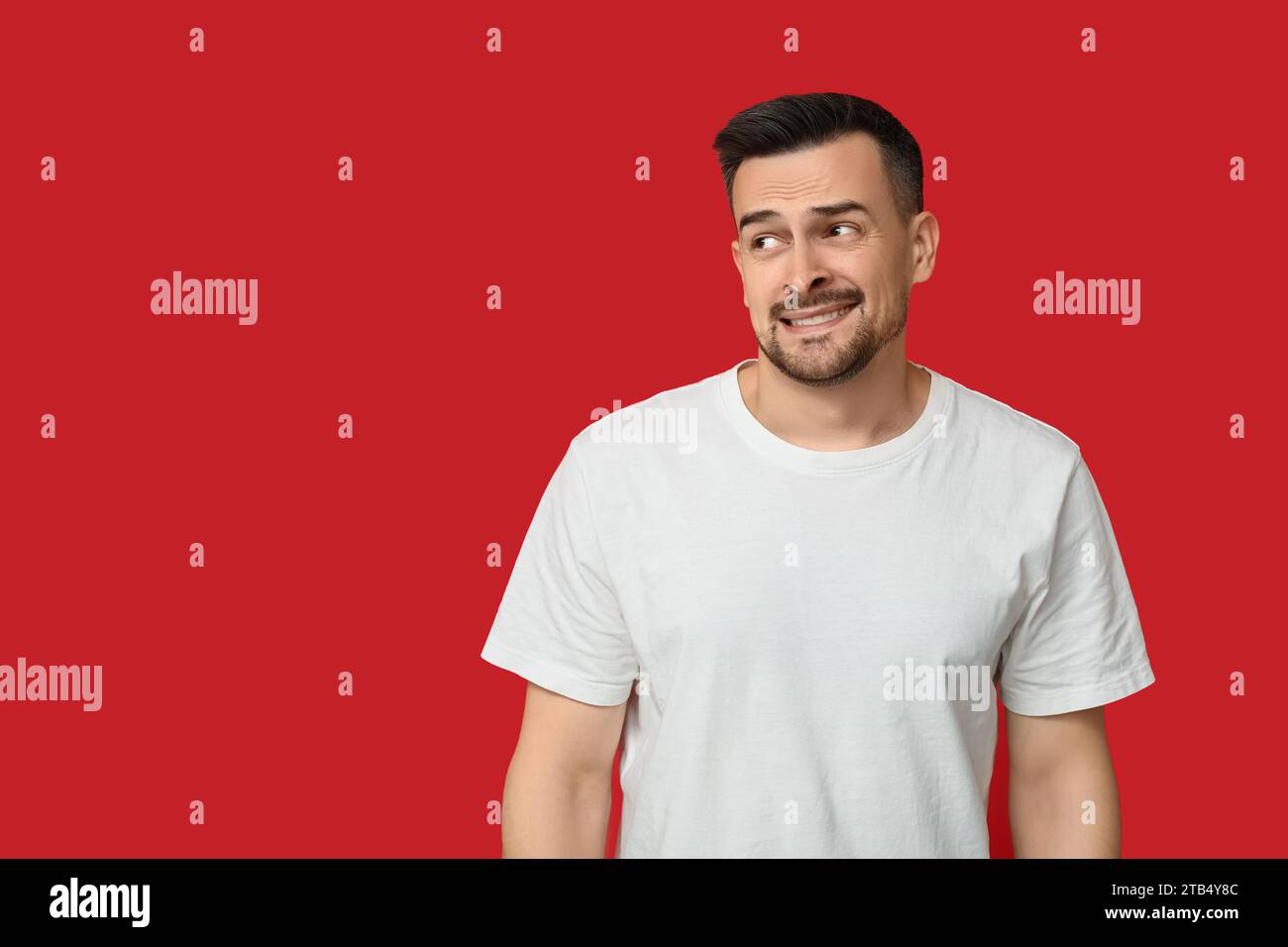 Handsome ashamed young man on red background Stock Photo - Alamy