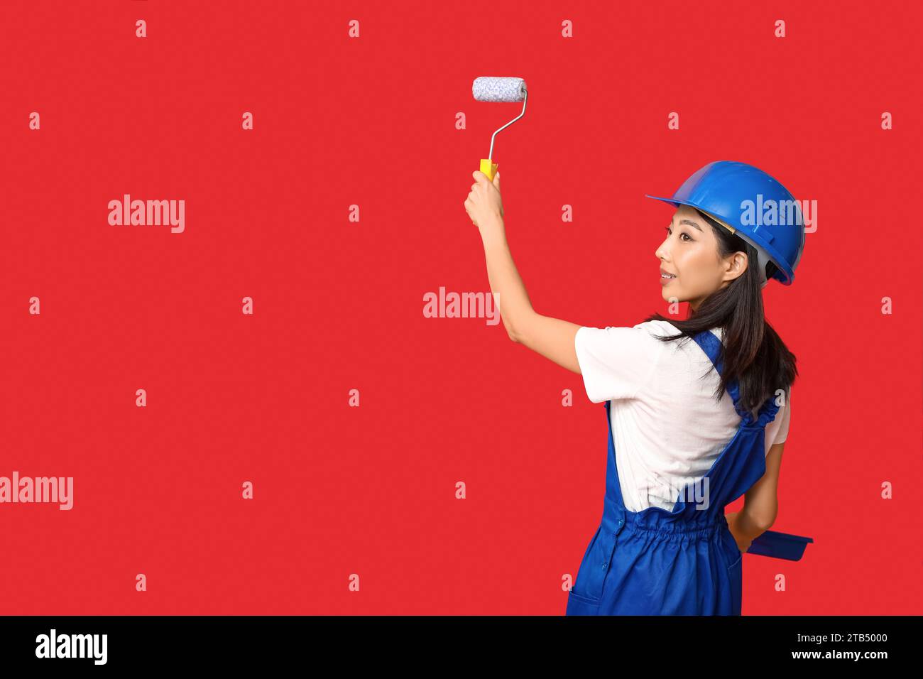 Female Asian painter with roller and tray on red background Stock Photo ...