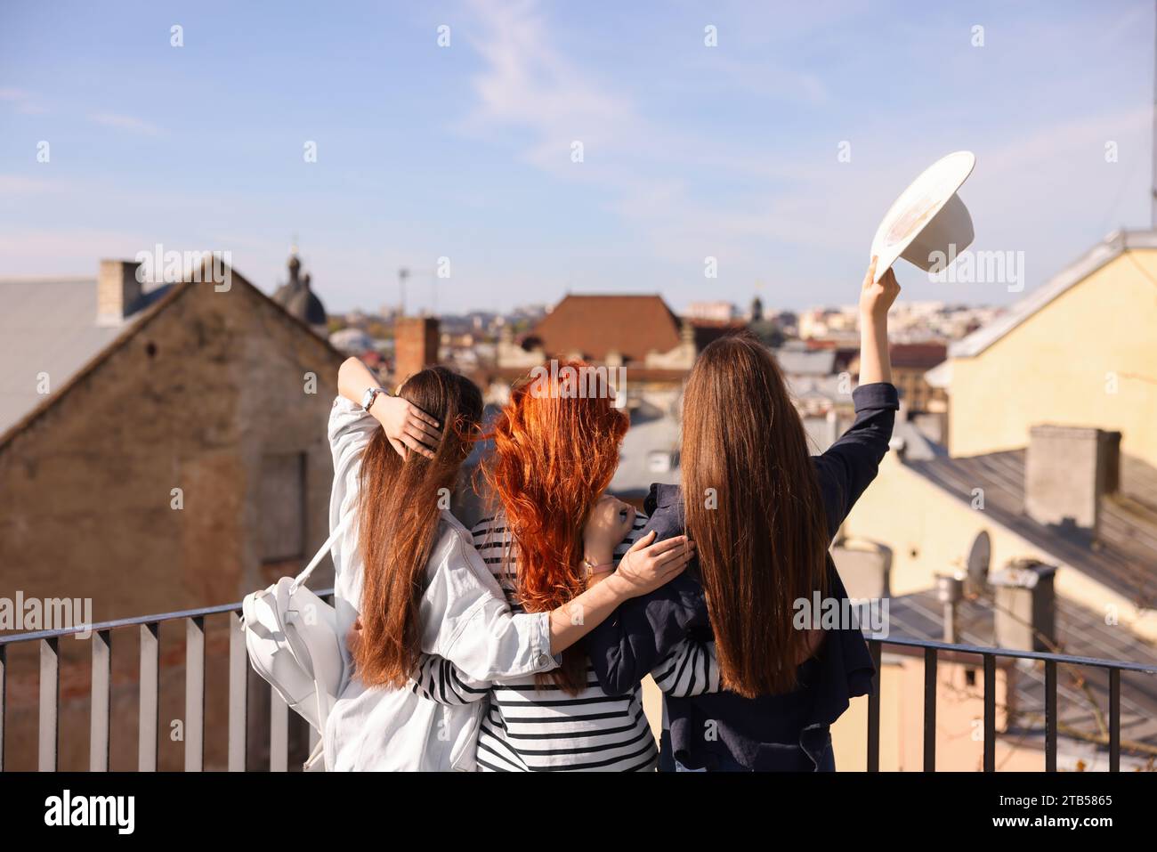 Friends enjoying of cityscape on balcony, back view Stock Photo - Alamy