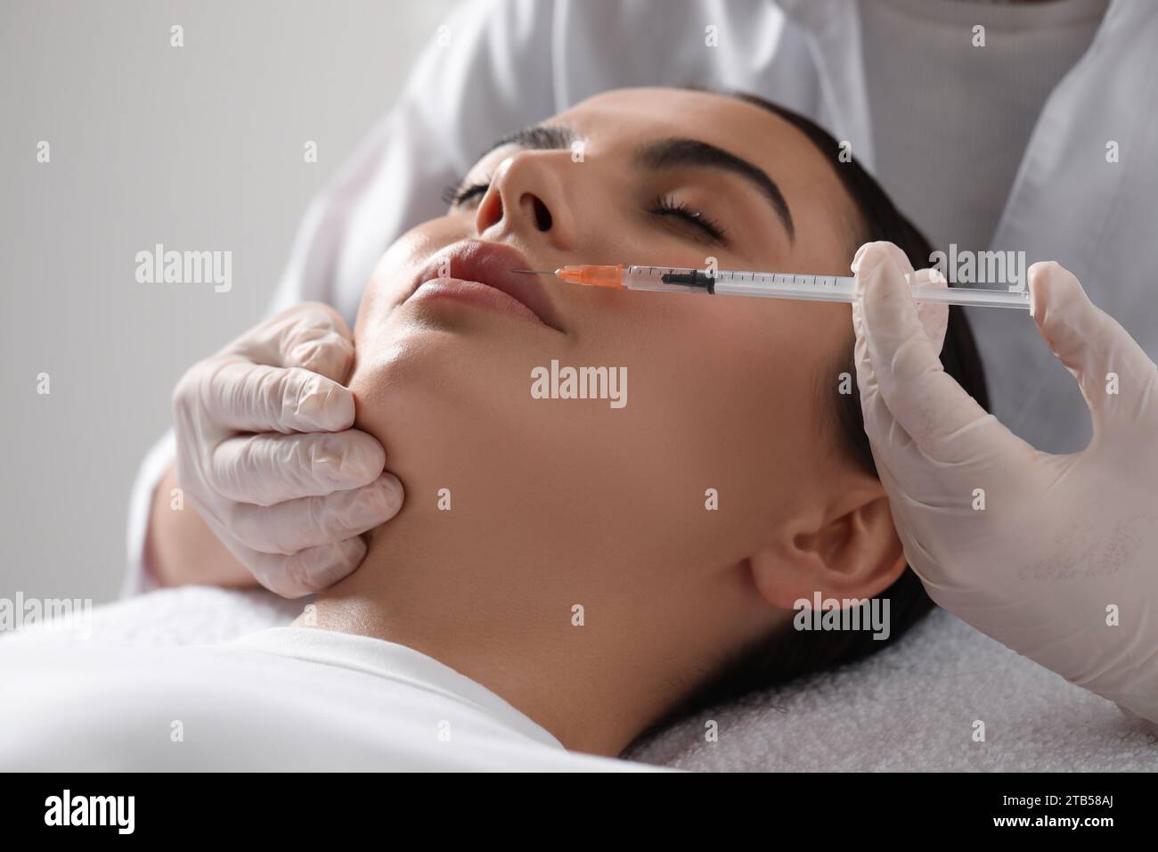 Doctor giving lips injection to young woman in clinic. Cosmetic surgery ...