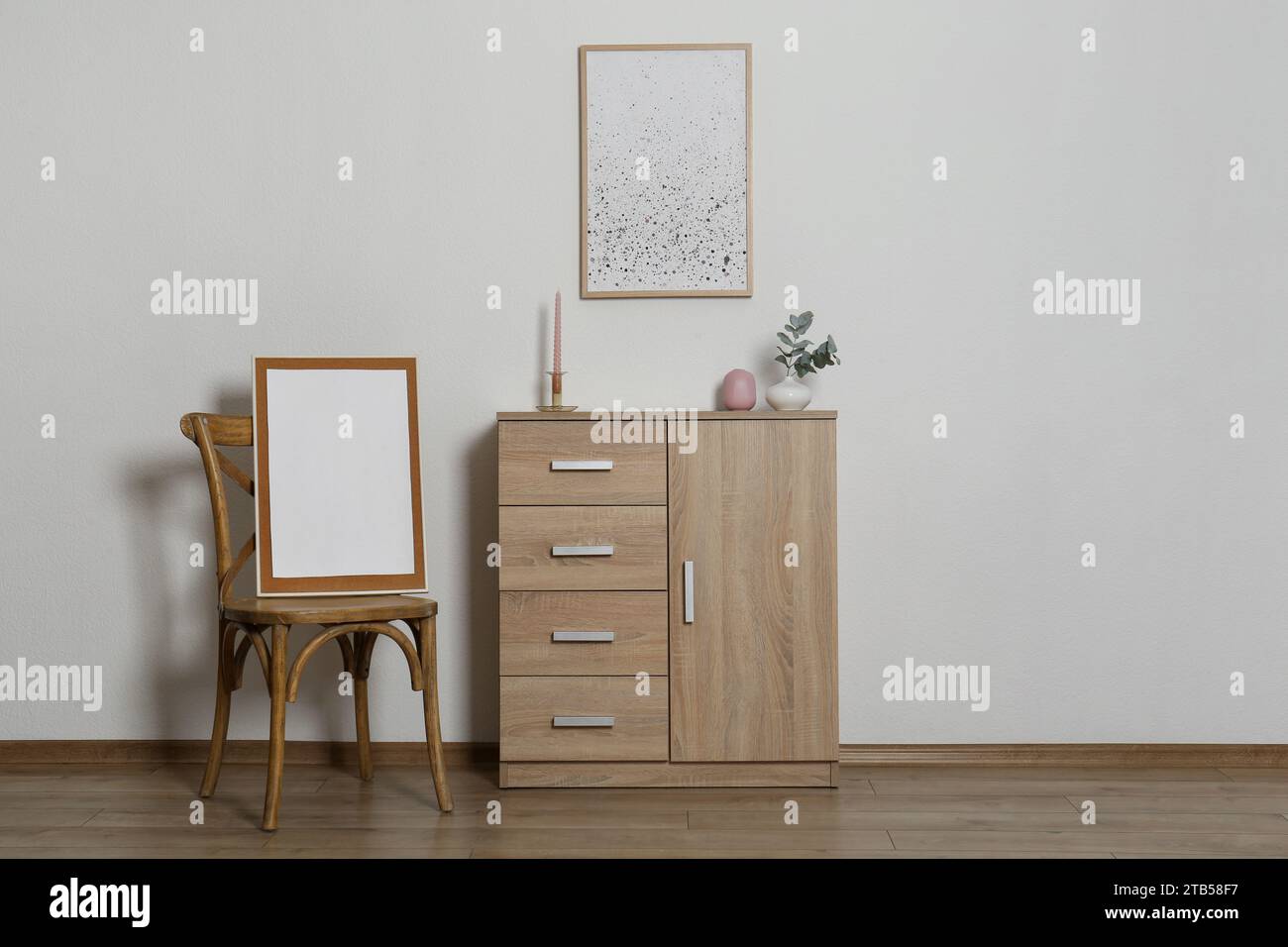 Wooden chair, chest of drawers, decorative elements and frames in room ...