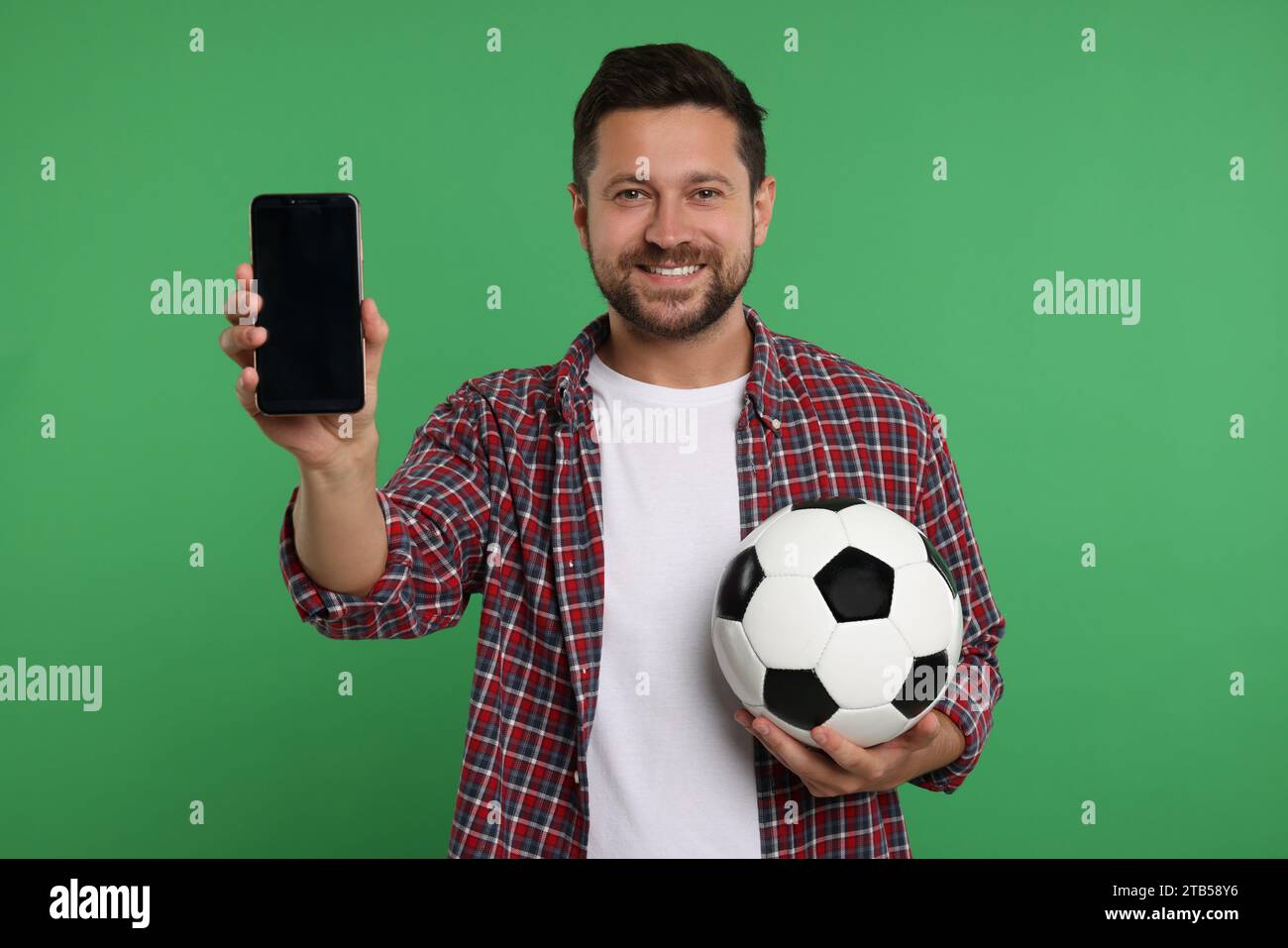 Happy sports fan with ball and smartphone on green background Stock ...
