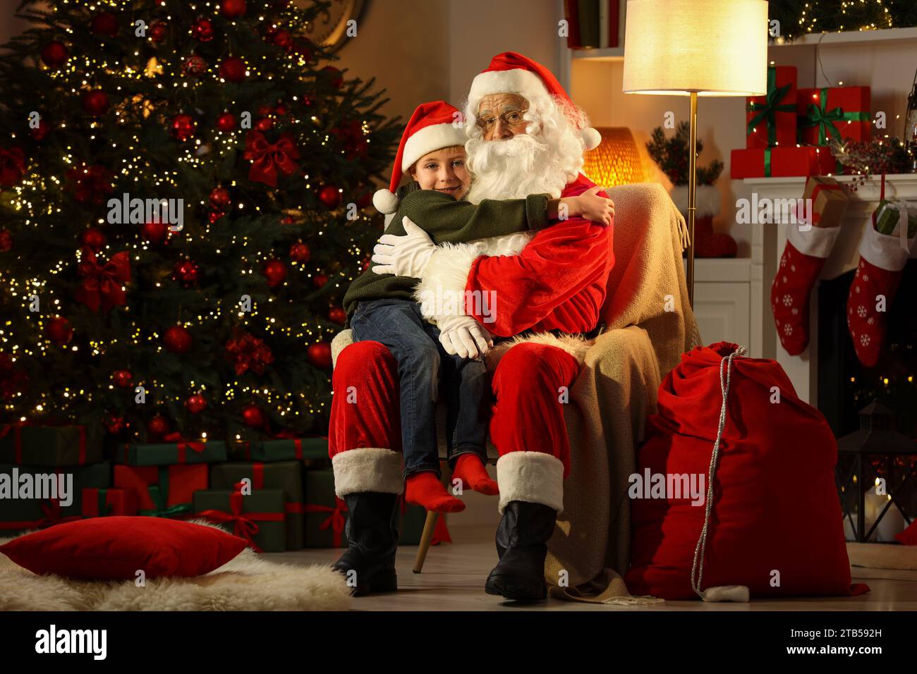Merry Christmas. Little boy hugging Santa Claus at home Stock Photo - Alamy
