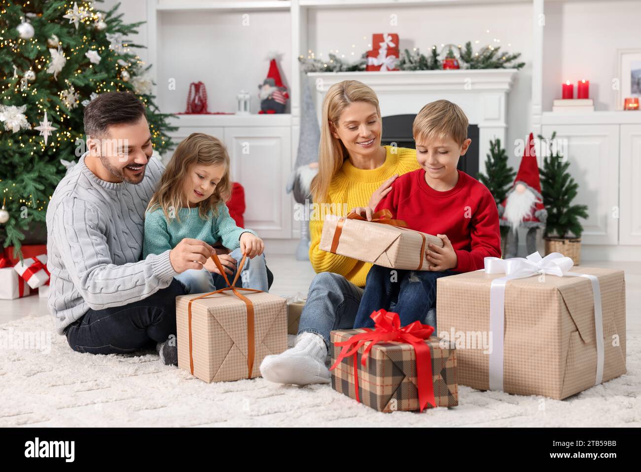 Parents and their children opening Christmas gifts at home Stock Photo ...