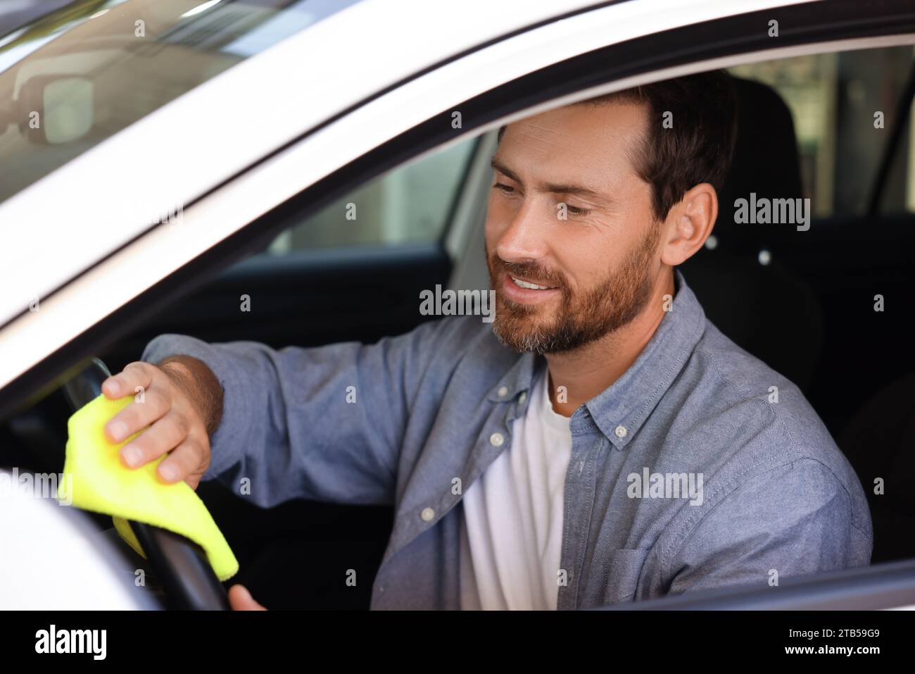 Man cleaning steering wheel with rag in car Stock Photo - Alamy