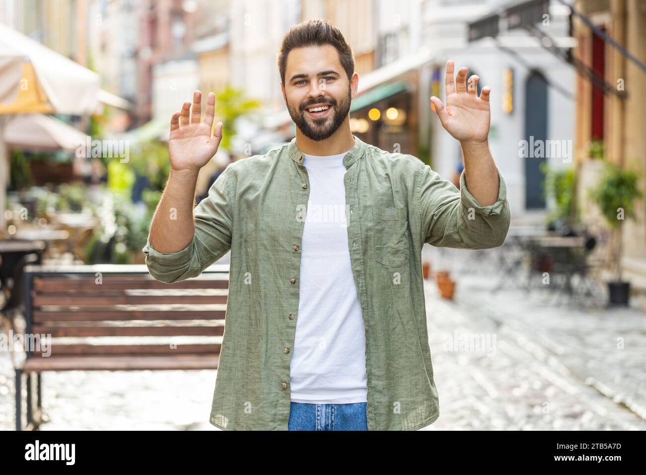 Bearded young man smiling friendly at camera, waving hands gesturing ...