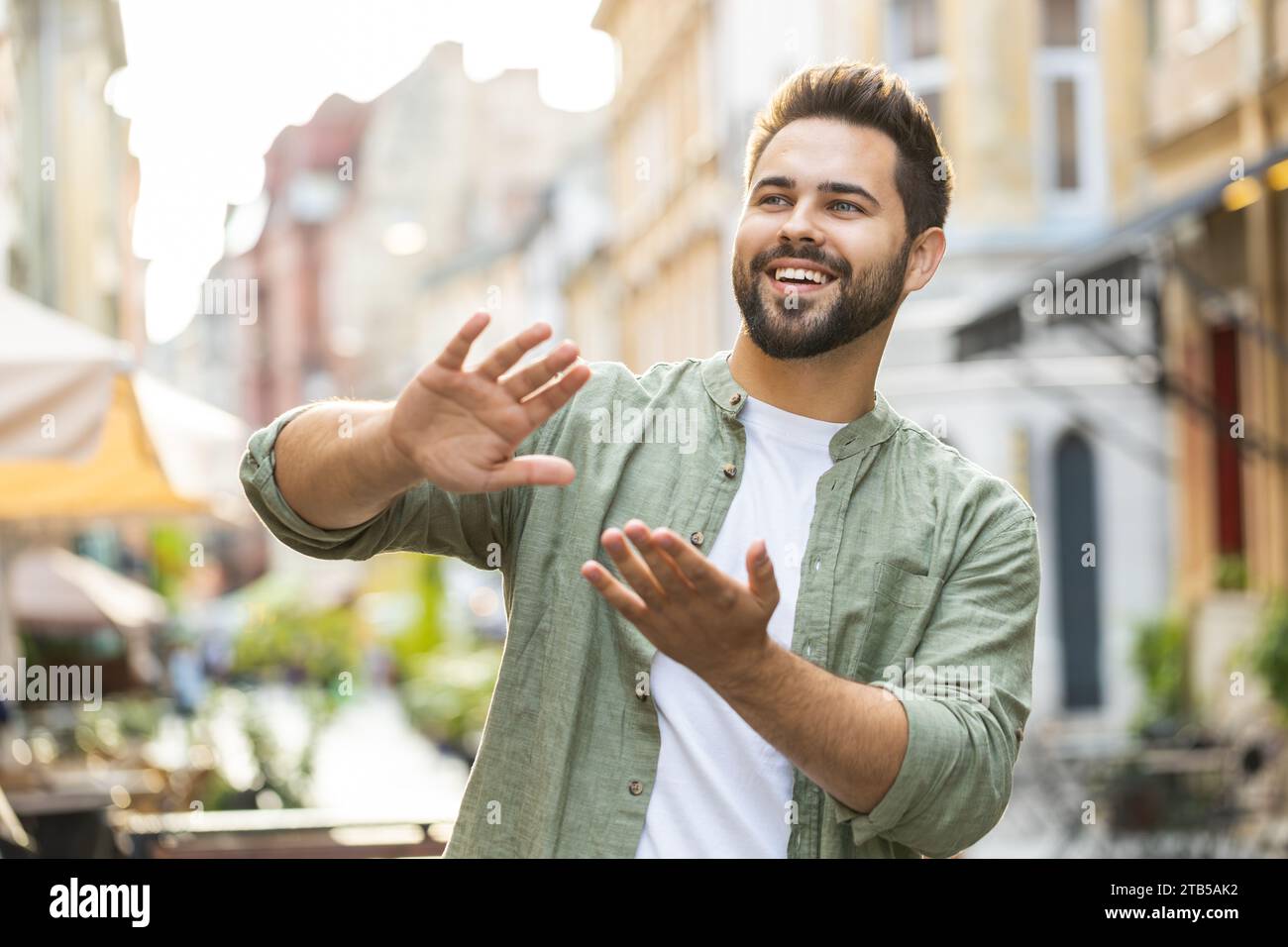 Cheerful rich bearded young man showing wasting throwing money around ...