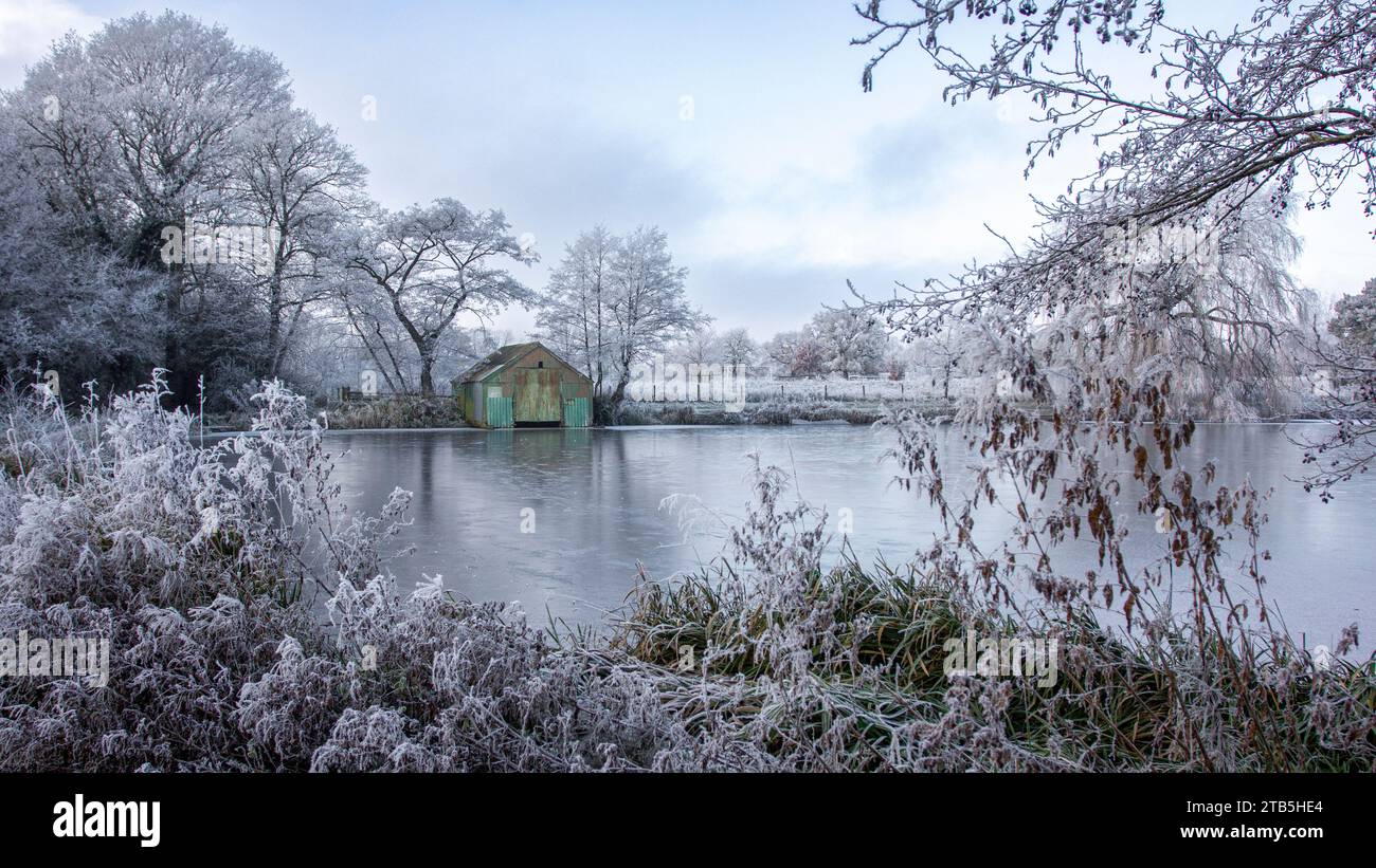 view across a frozen pool towards an old corrugated boat house. Taken ...