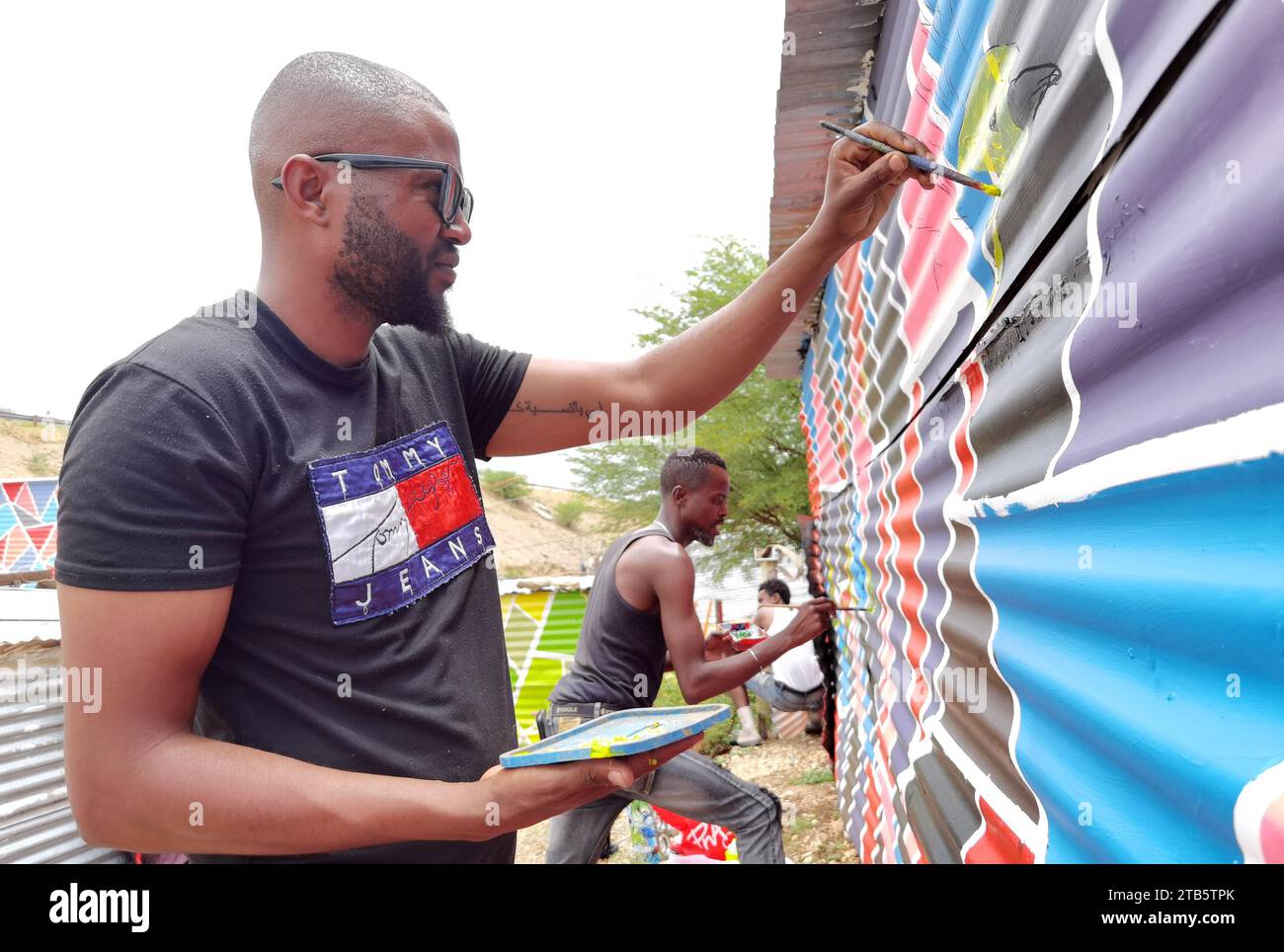 Windhoek, Namibia. 4th Dec, 2023. Artist Ndako Nghipandulwa (L) paints ...