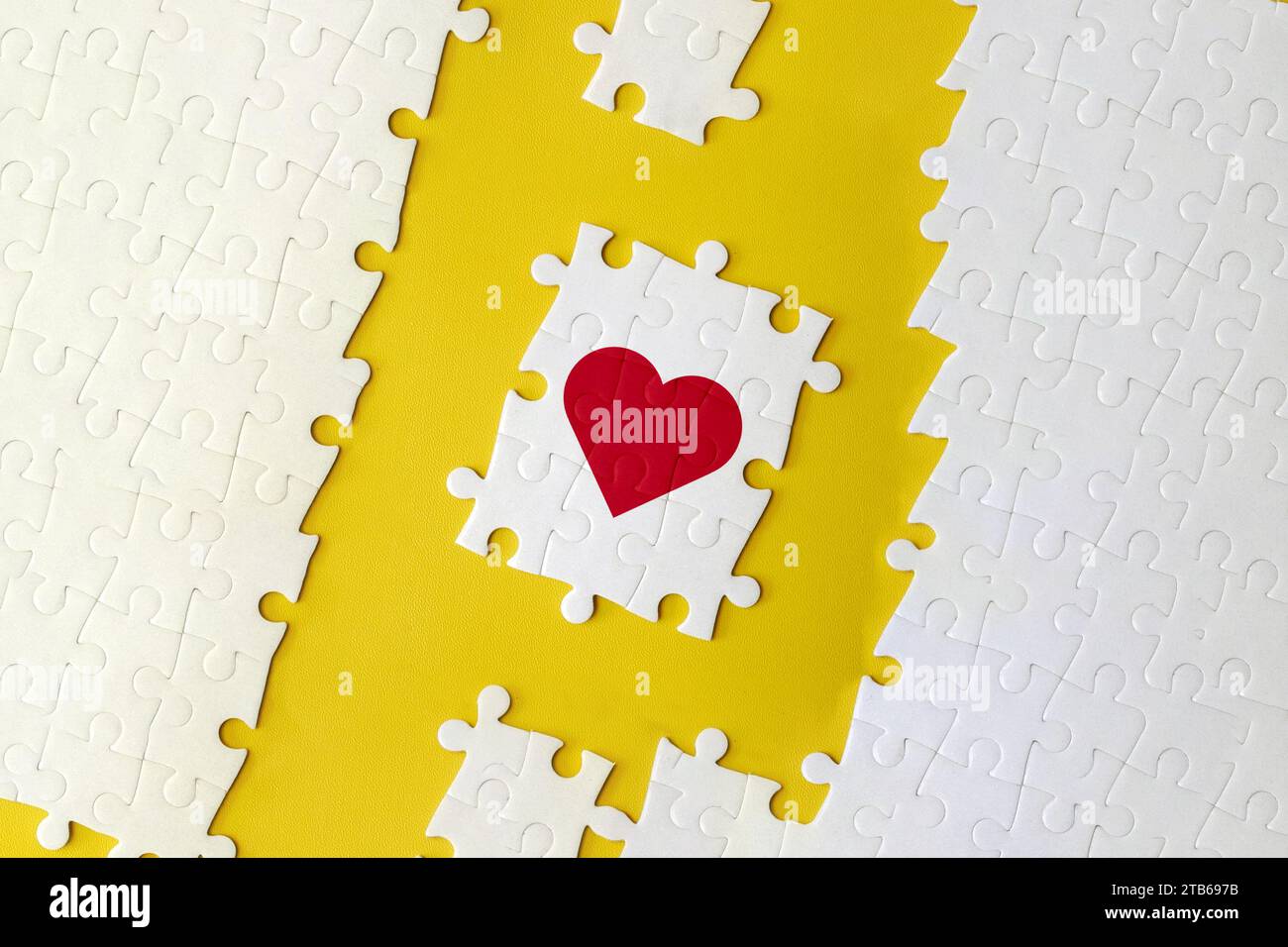 Puzzle pieces that make up a heart on the yellow background. The ...
