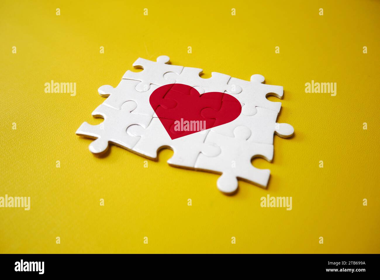 Puzzle pieces that make up a heart on the yellow background. The ...
