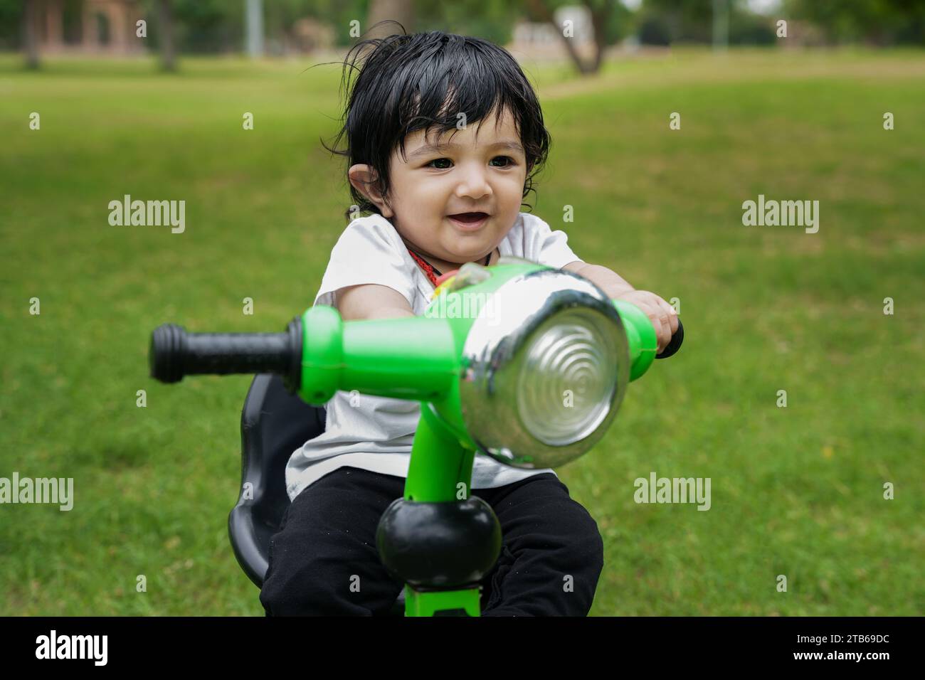 Cute little toddler rides the tricycle. Toddler using bike at park or ...