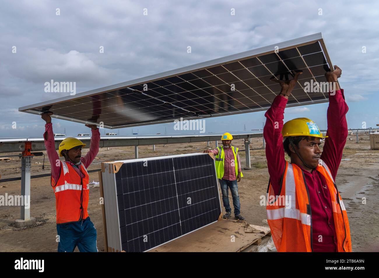 Workers carry a solar panel for installation at the under-construction Adani Green Energy ...