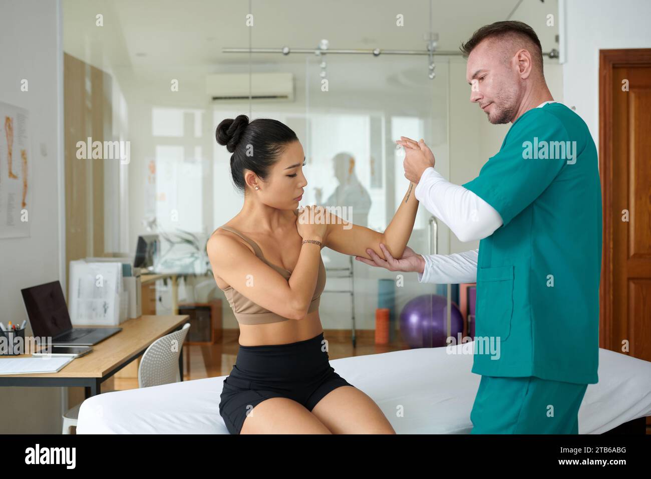 Rehab doctor checking shoulder mobility of injured sportswoman Stock Photo - Alamy