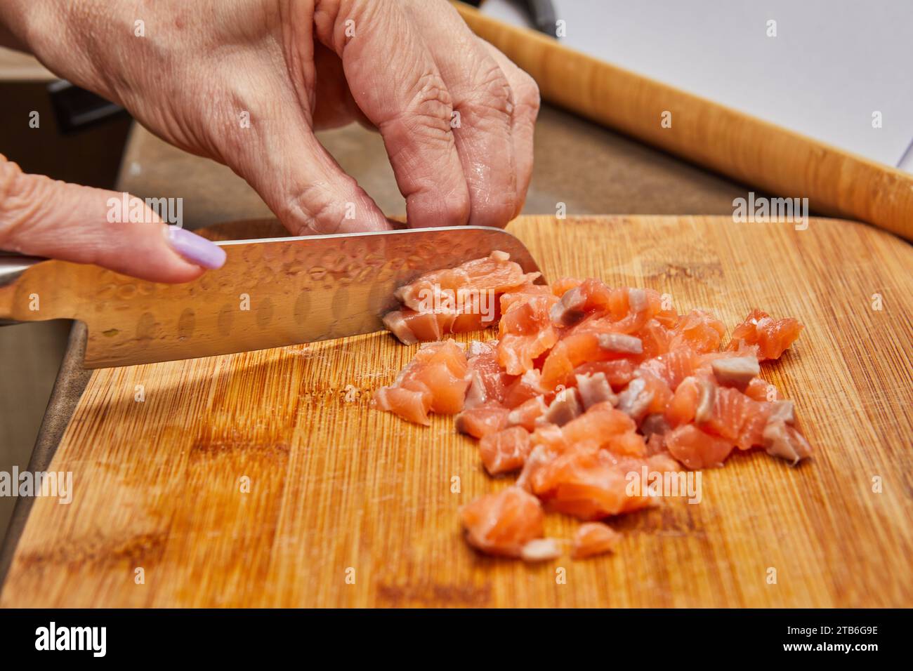 A skilled chefs hands carefully cutting a piece of fresh salmon using a ...