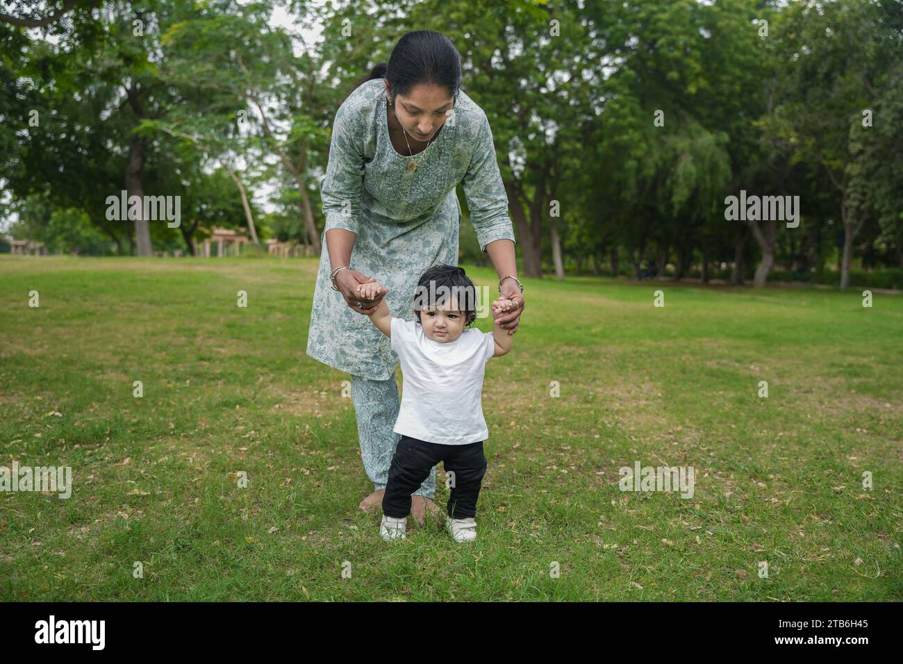 Young indian mother with her cute looking boy walking in garden, Teaching her boy to walk Stock ...