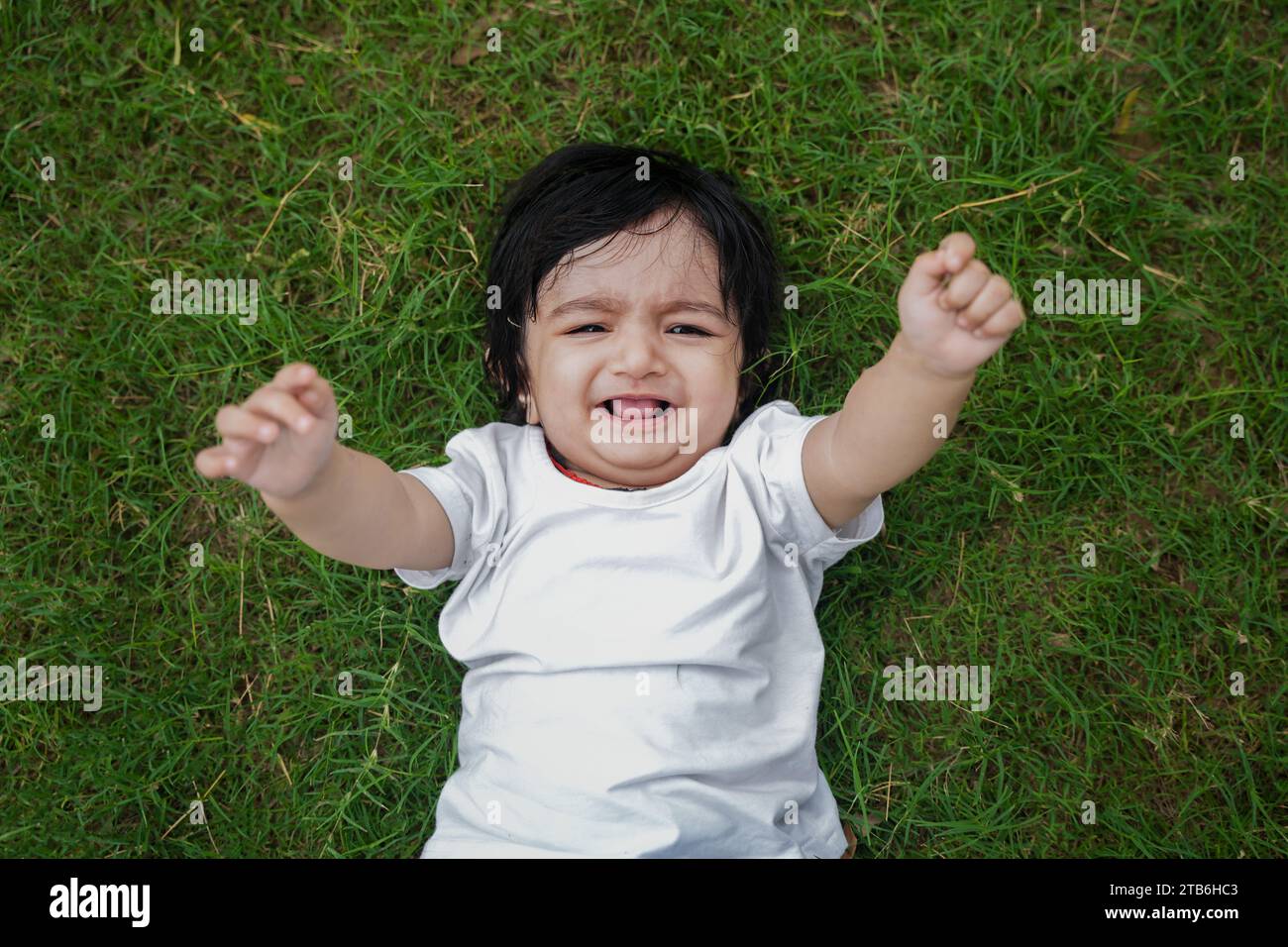 Cute indian boy lying in garden crying Stock Photo - Alamy