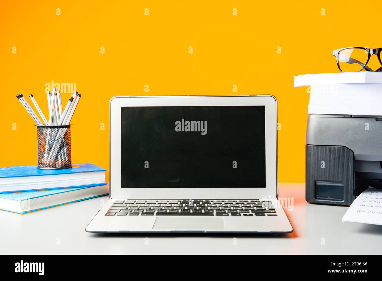 Laser printer and laptop on desk against yellow background Stock Photo ...