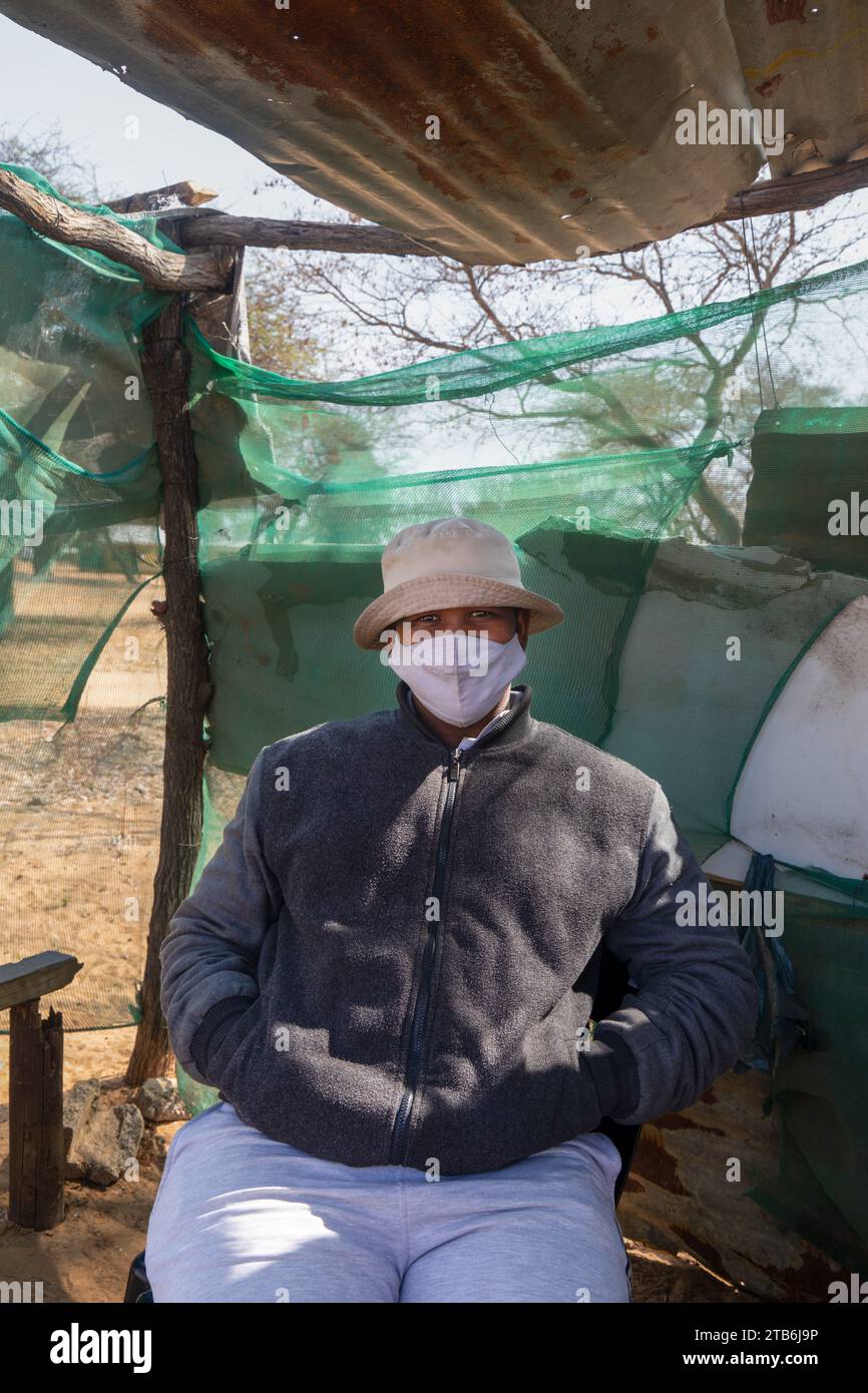 villager young african man with a hat wearing a mask in a shanty town ...