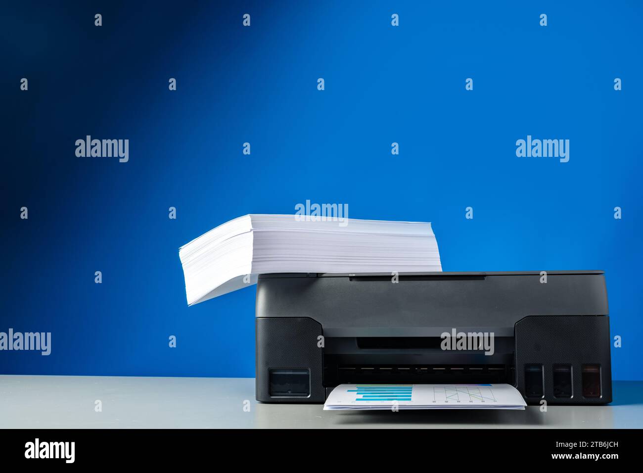 Laser printer on desk against blue background Stock Photo - Alamy