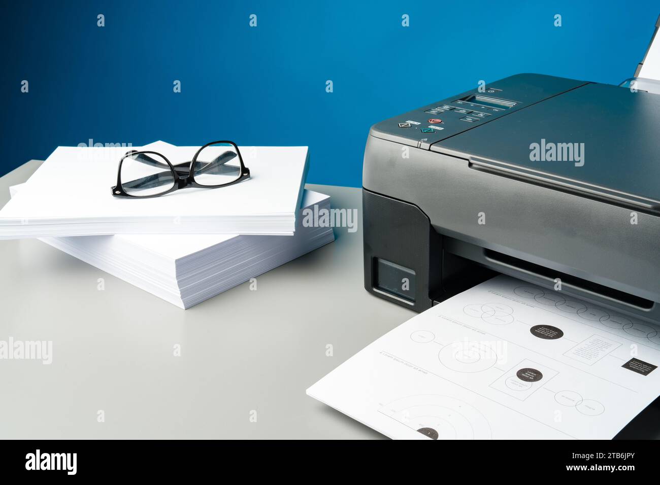 Laser printer on desk against blue background Stock Photo - Alamy