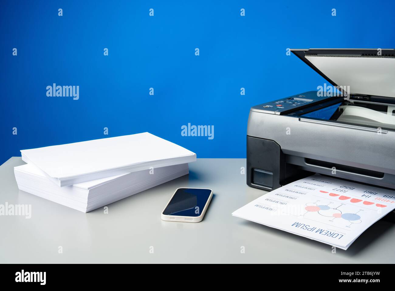 Laser printer on desk against blue background Stock Photo - Alamy