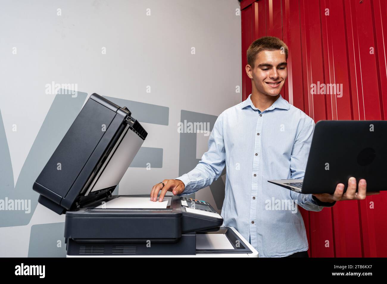 Positive young man using printer in the modern office Stock Photo - Alamy