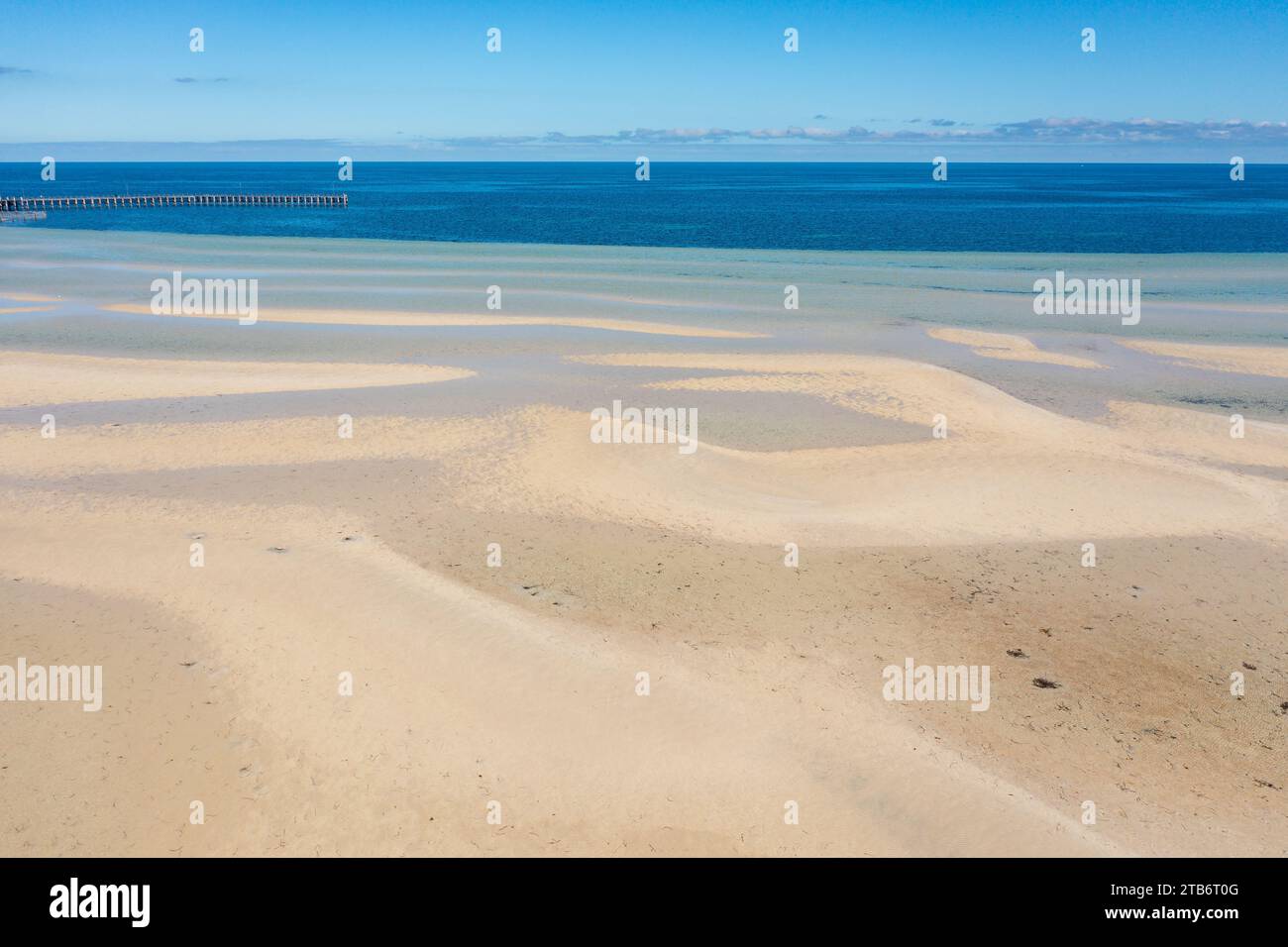 Aerial view of pools of water on a white sandy beach formed in long ...