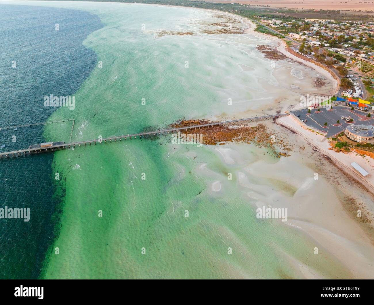 Aerial view of a long narrow jetty running over rocks and a wide beach ...