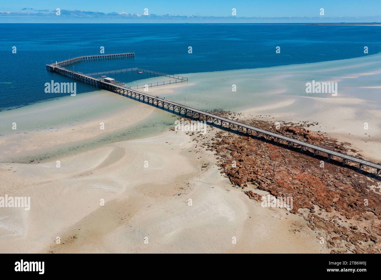 Aerial view of a long narrow jetty running over rocks and beach to ...