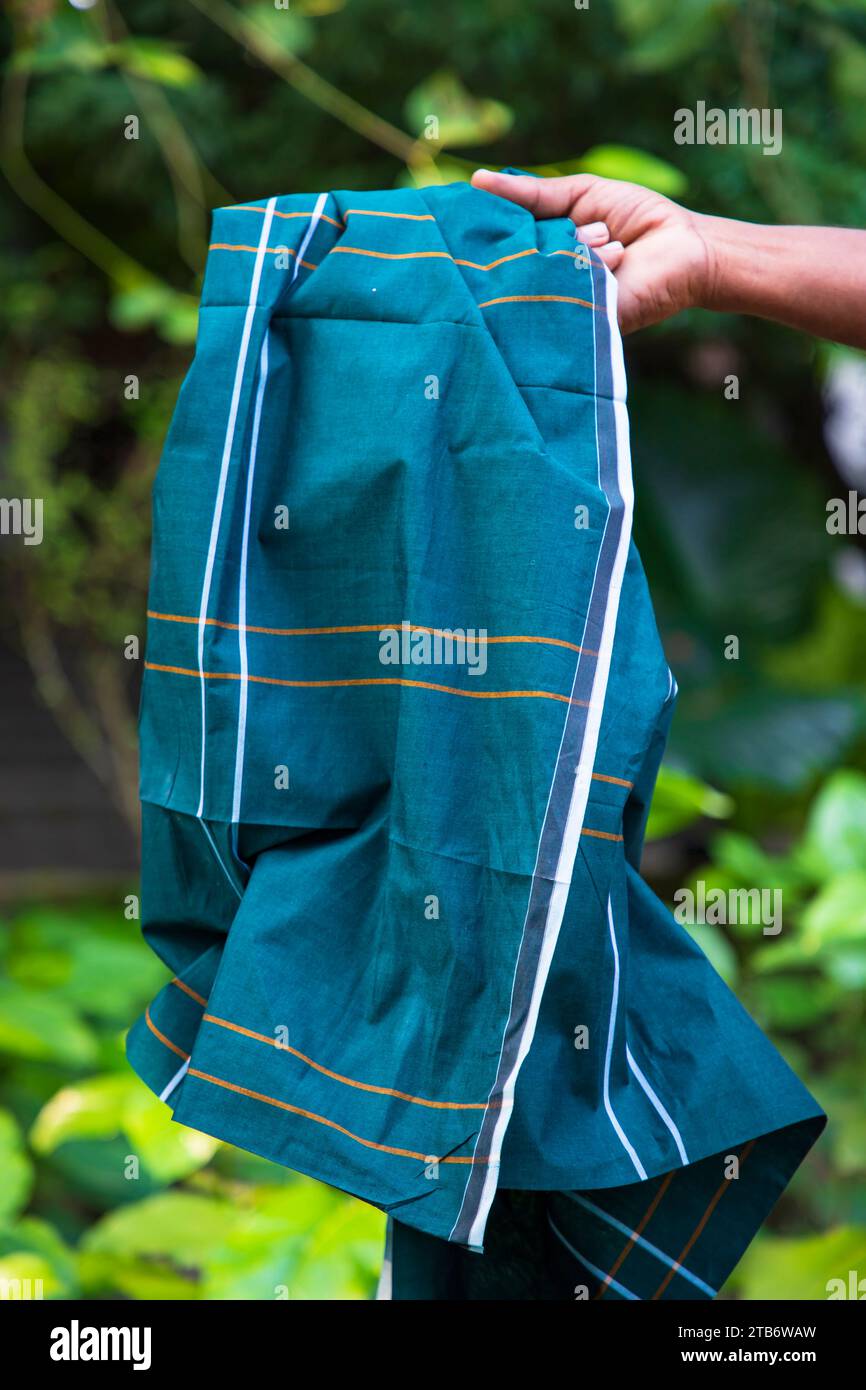 Folded Cotton Fabric Lungi hand holding with Green Blurry Background ...