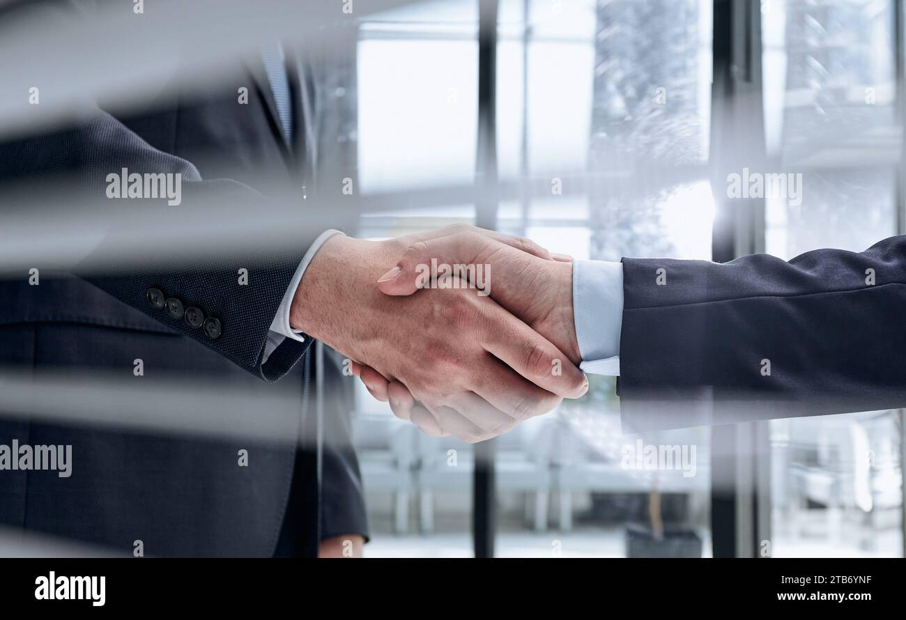 executives shaking hands in front of their manager and a colleague ...