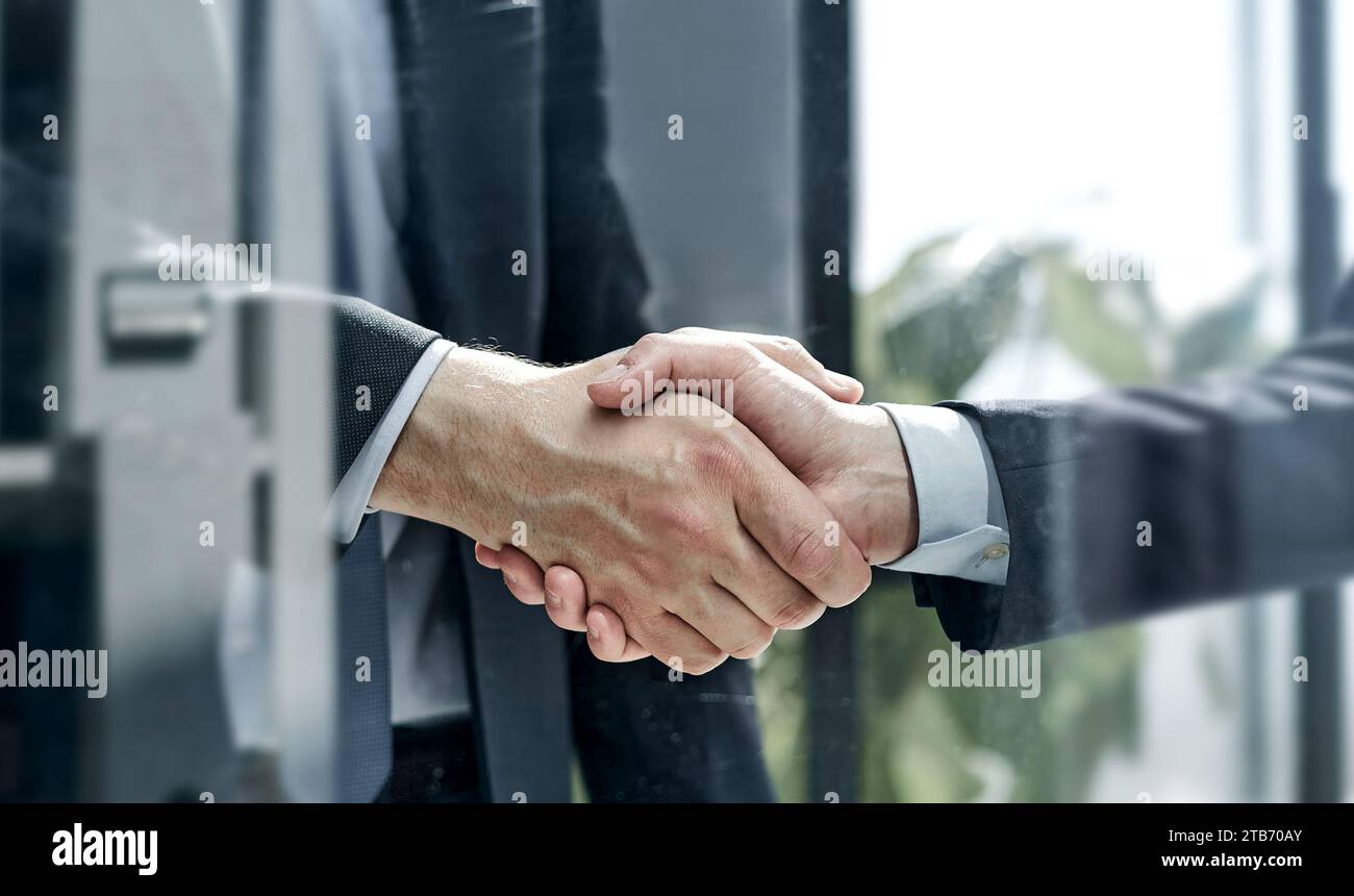 executives shaking hands in front of their manager and a colleague ...