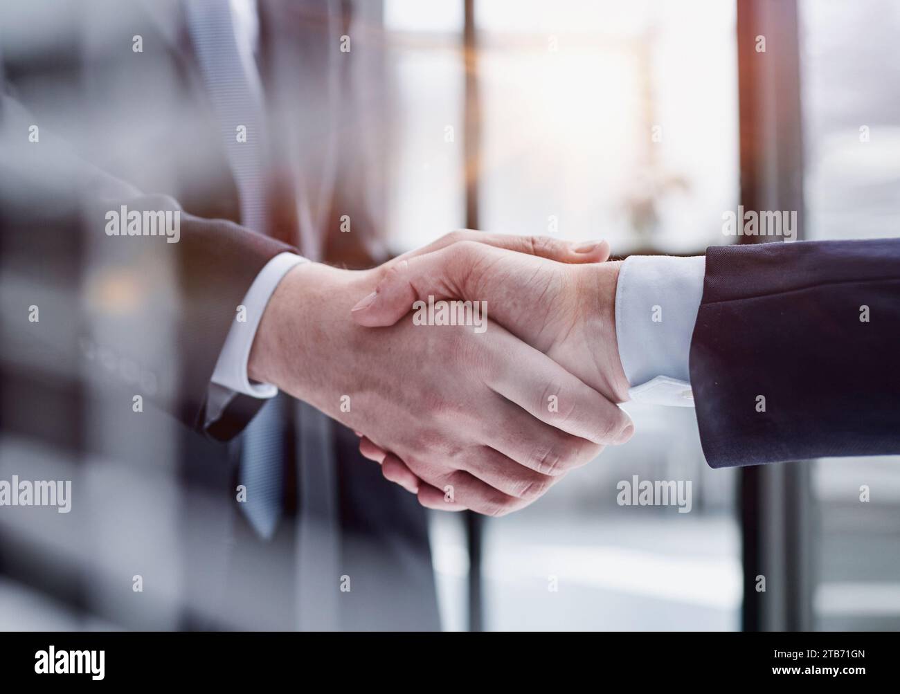 executives shaking hands in front of their manager and a colleague ...