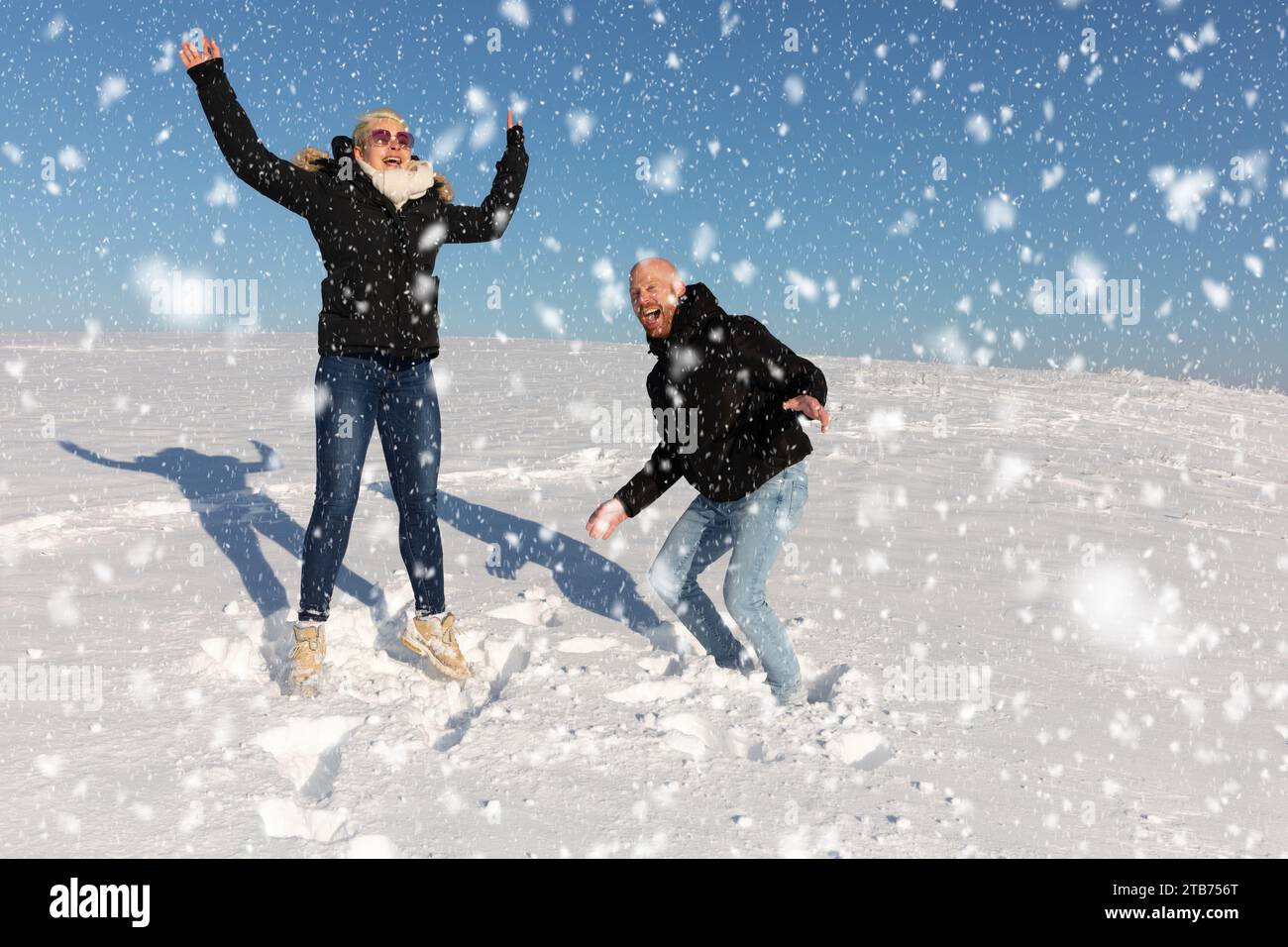 A young couple, consisting of a woman and a man, jump in the air in the ...