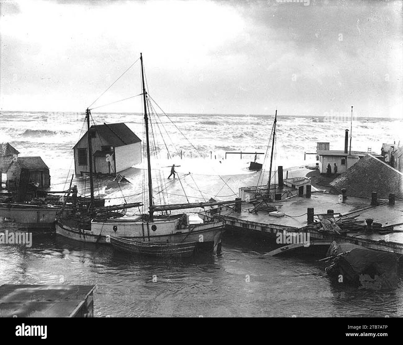 Waves washing houses off of the sand spit during a storm, Nome, Alaska ...