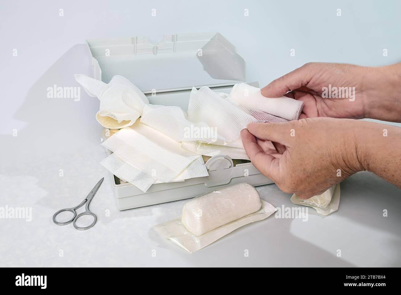 Hands taking out a bandage from a first aid kit with medical supplies ...