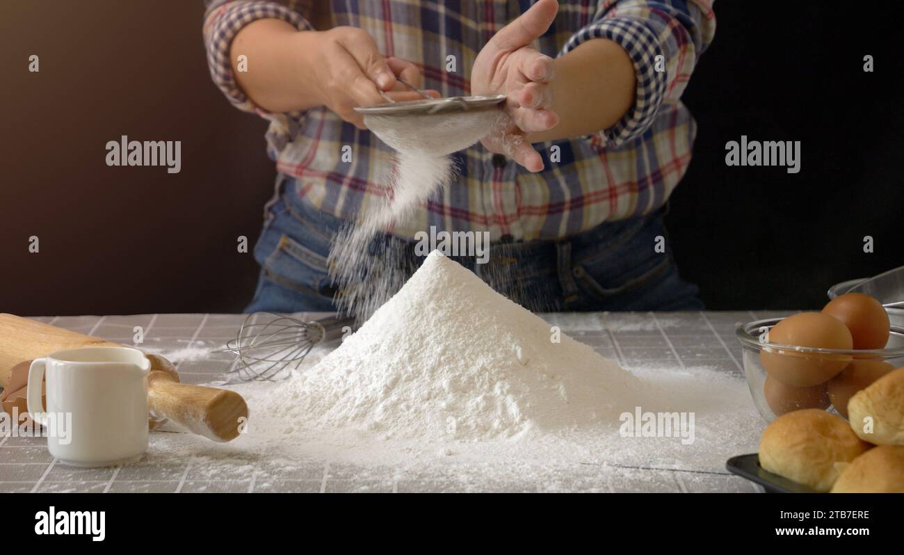 artisan bread working with dough. Use a sieve to sift flour into dough ...