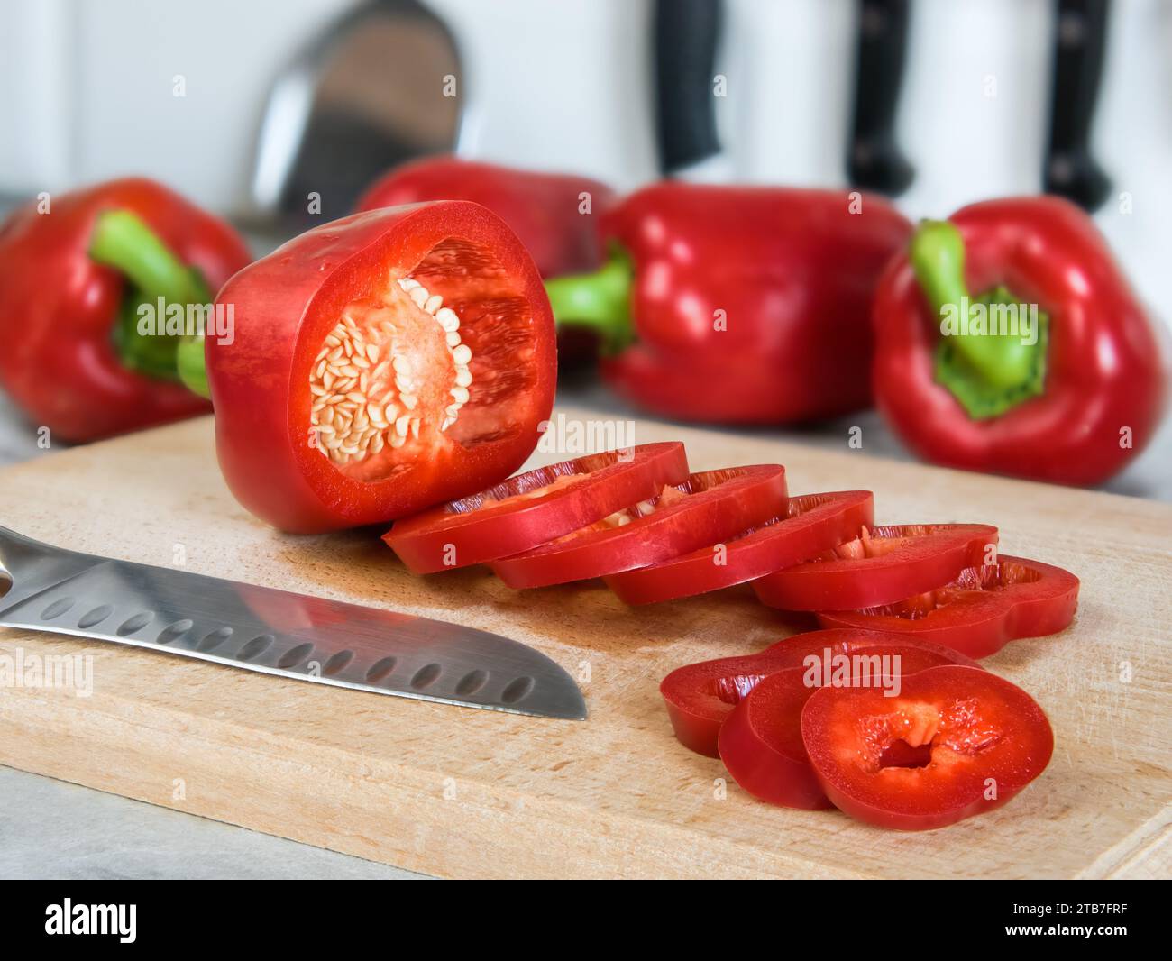 Santoku knife and slised red pepper (paprika, capsicum) on a beech wood ...