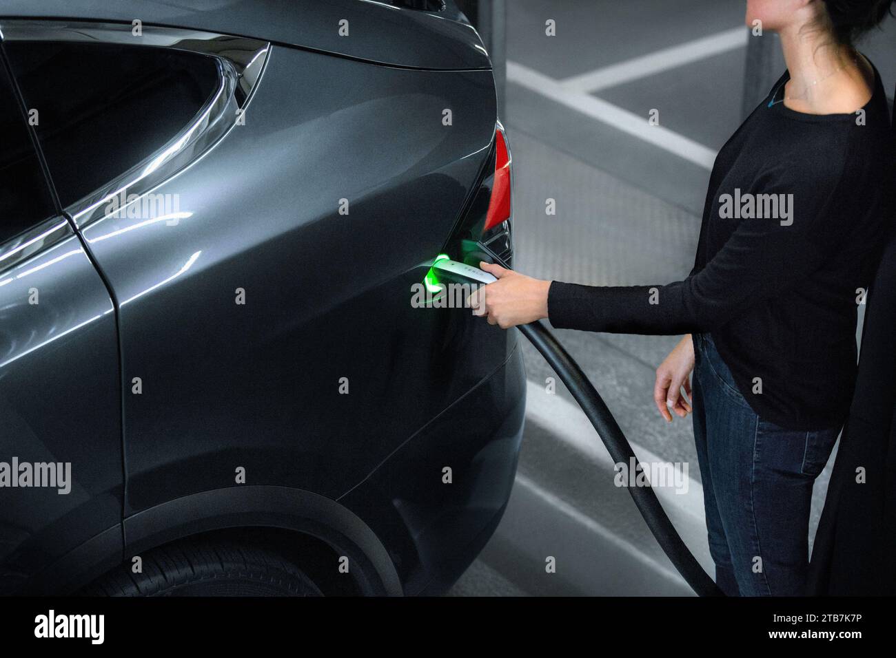 Woman using the Tesla Wall Connector, fast charging solution for ...