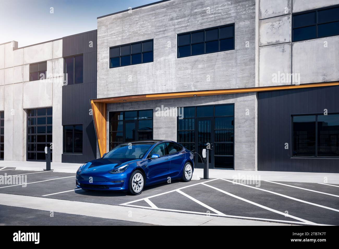 Charging a Tesla electric vehicle in the parking lot of an office ...