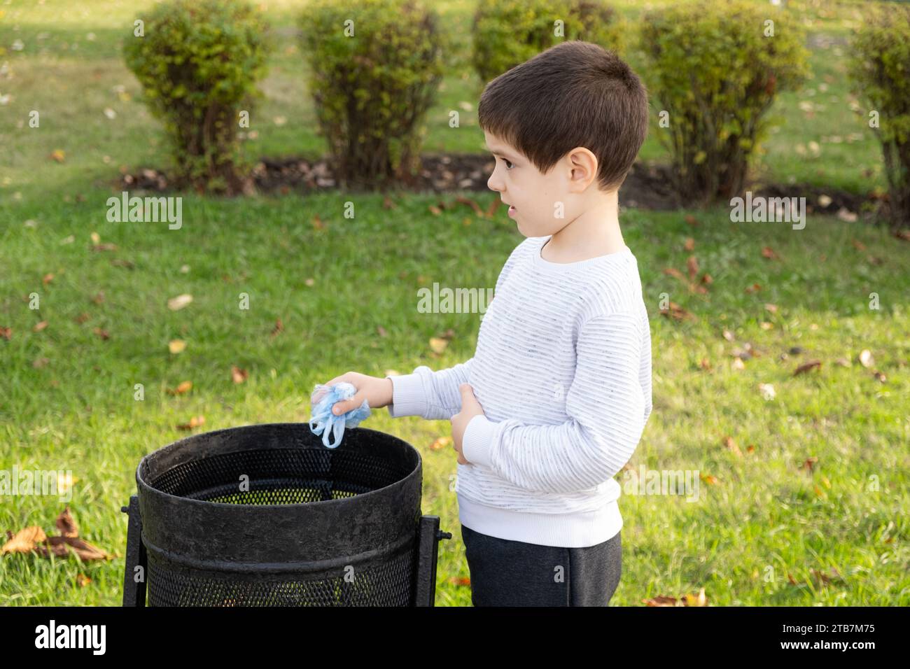 A child throws a plastic bag in the trash. Concept of garbage recycling ...