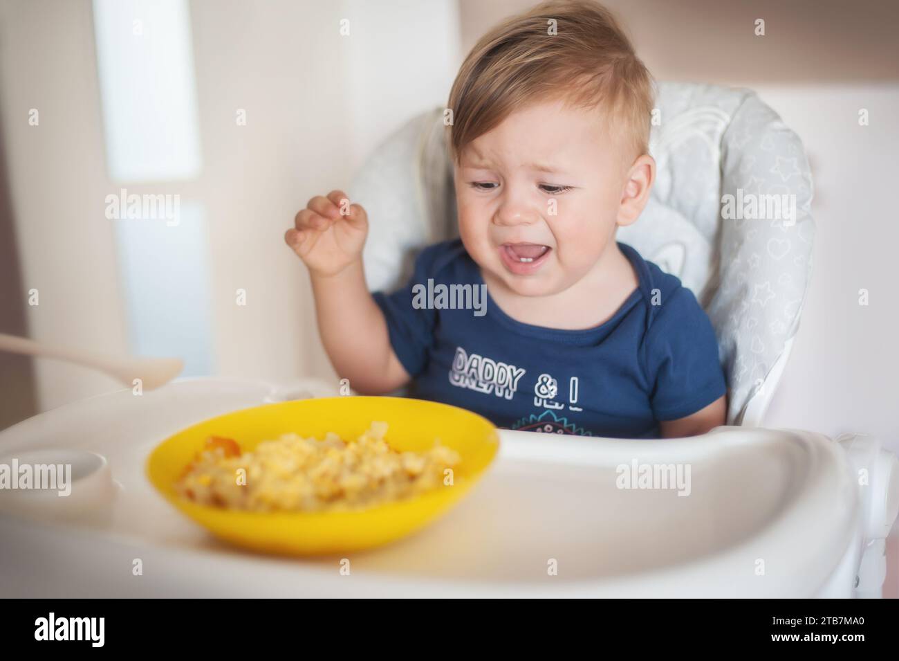 Portrait of adorable baby boy sitting on the chair and crying while ...