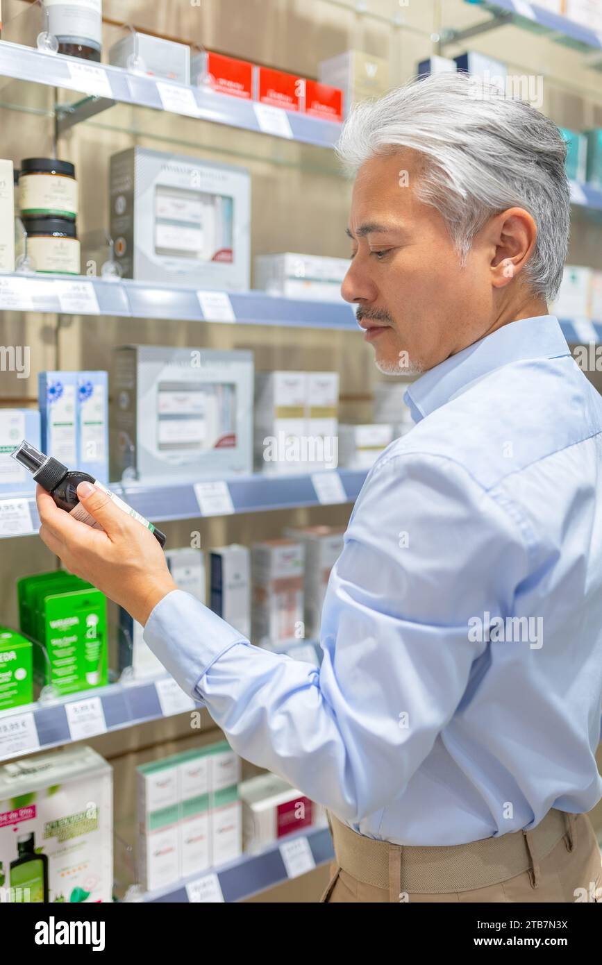 Senior man holding product and checking information while standing by ...