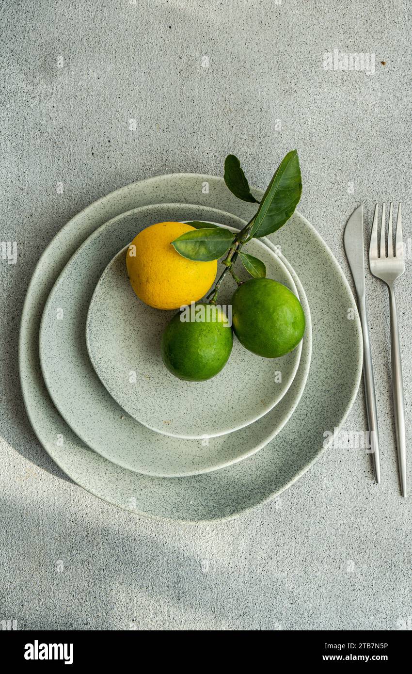 Overhead shot of stacked ceramic plates with a lemon and two limes ...