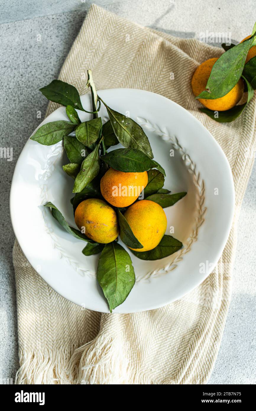 Fresh tangerines on a classic white plate over a textured beige napkin ...